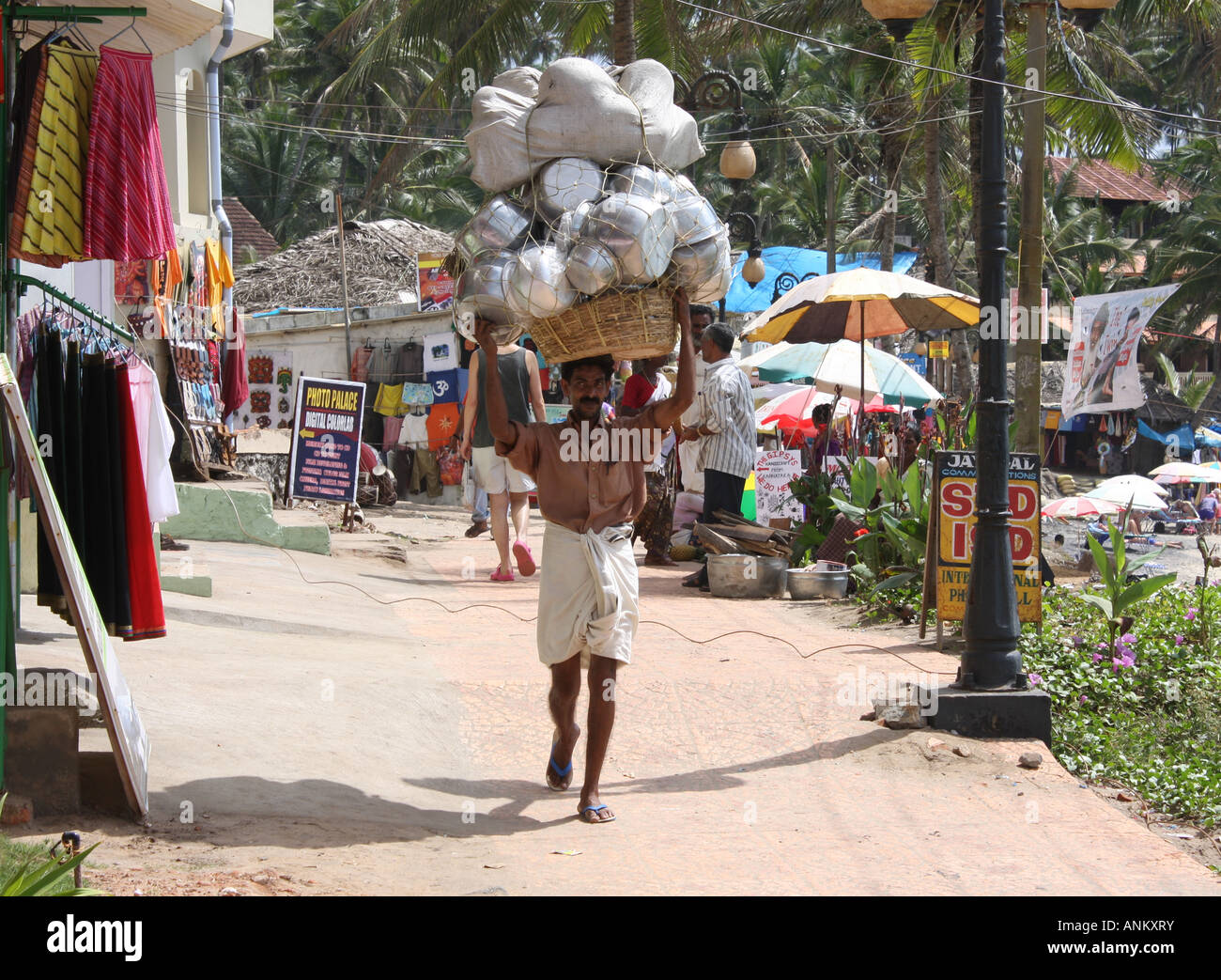 Indian man carrying pots on his head by the beach in Kovalam, Kerala ...