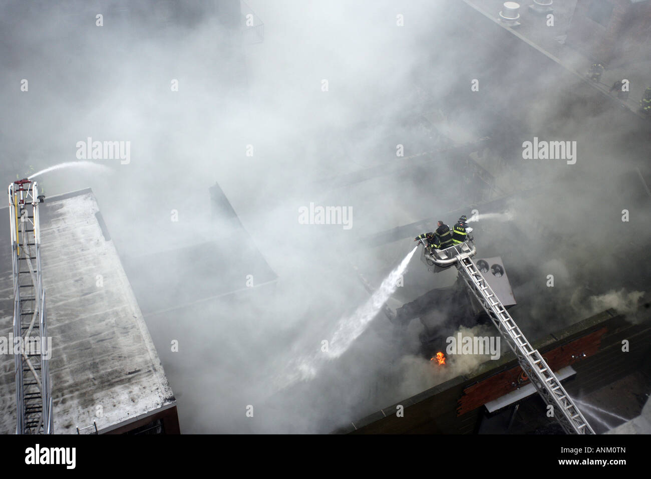 Firefighters on a Ladder truck battle a massive three-alarm fire Stock ...
