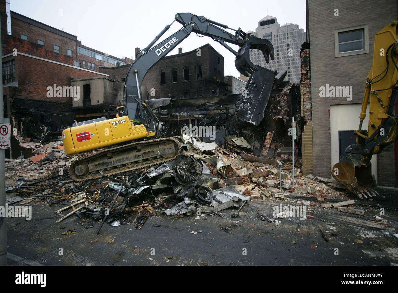 A backhoe wrecker tears down a building after a fire Stock Photo - Alamy