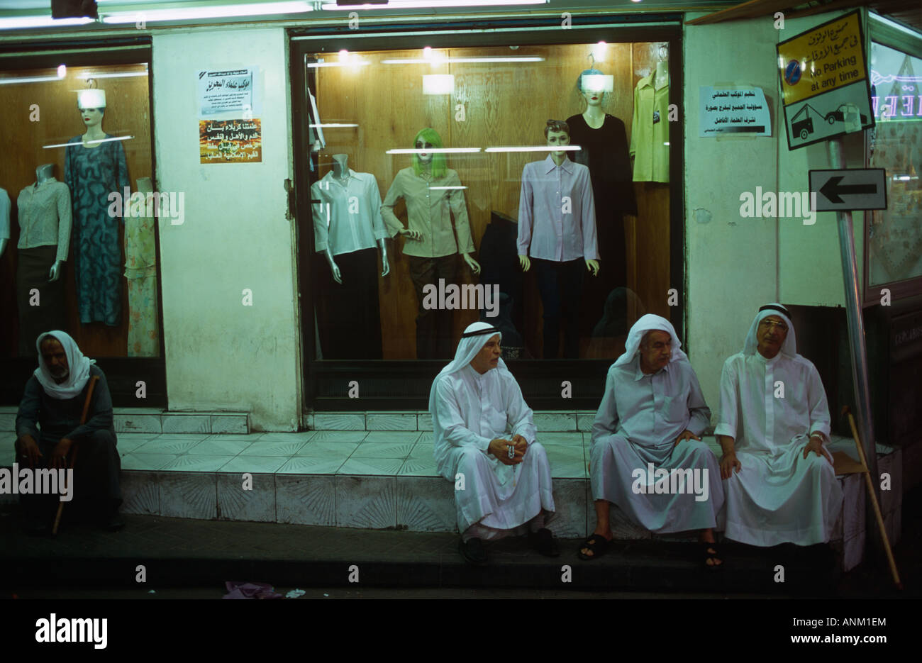 Middle-aged men sit chatting on a Manama City street pavement behind a ...