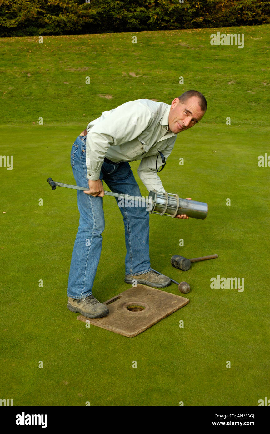 Head green-keeper making new hole on golf course green Stock Photo - Alamy