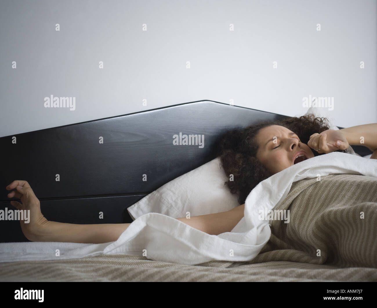 Woman lying on the bed and yawning Stock Photo - Alamy