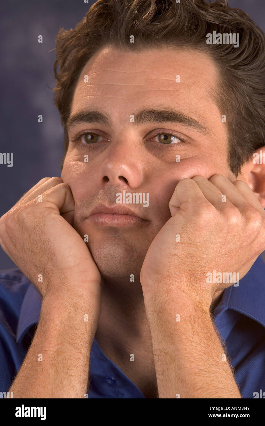 Man looking bored resting his chin in his hands Stock Photo - Alamy