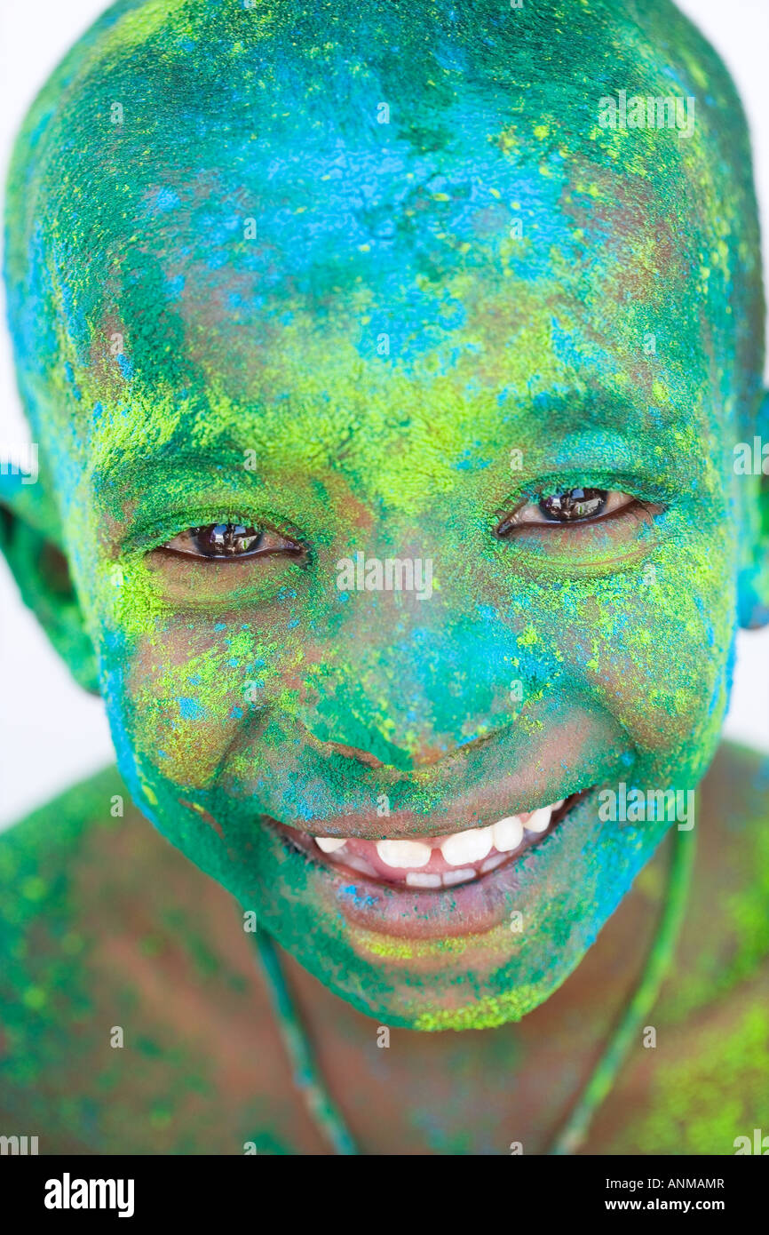 Young Indian boy covered in coloured powder pigment with a cheeky smile ...