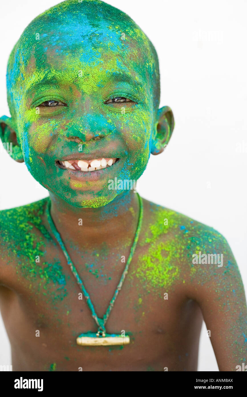 Young Indian boy covered in coloured powder pigment with a cheeky smile ...