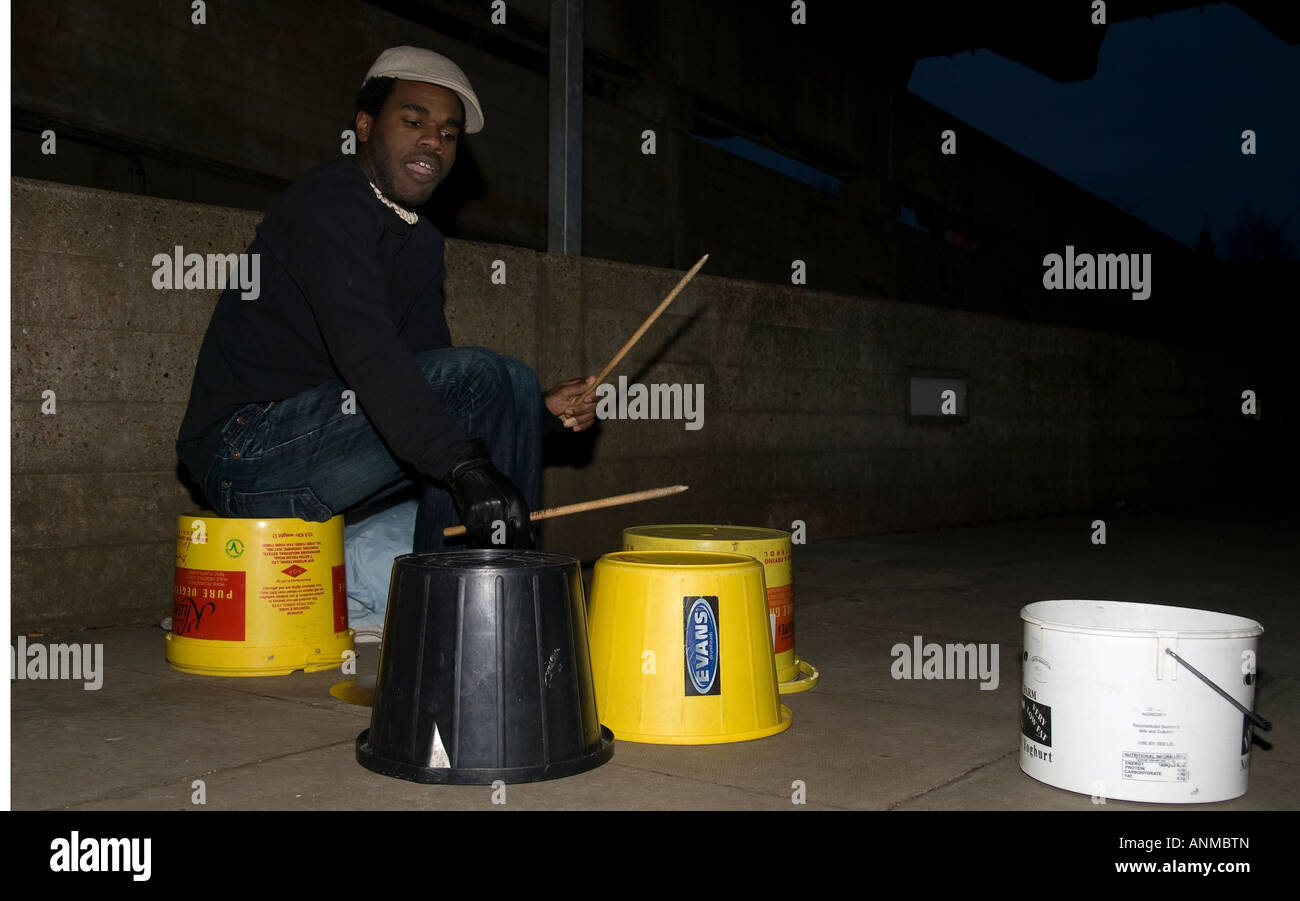Young man busking playing drums on upturned plastic buckets on London's ...