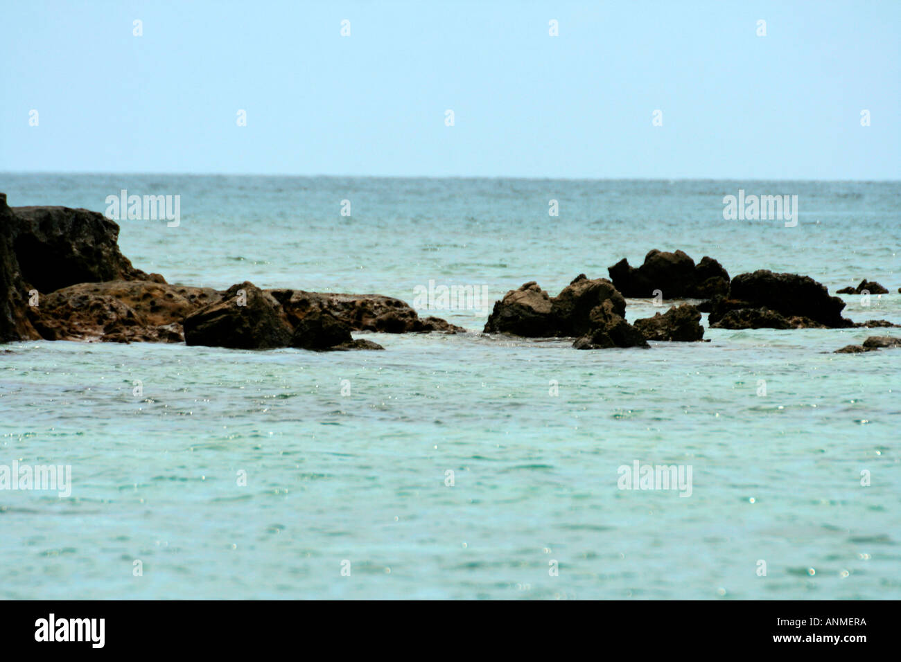 Rocks in mid sea with a view of forests in the distance in Jolly buoy ...
