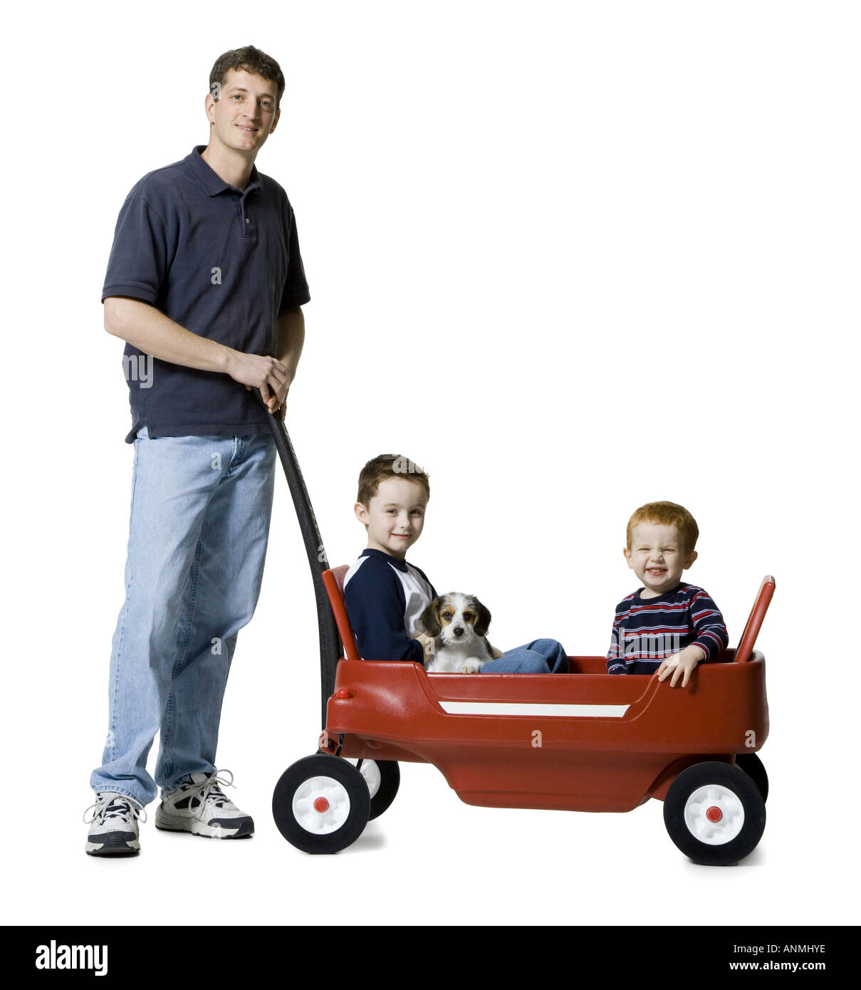 Portrait of a father standing with his two sons sitting in a wagon ...