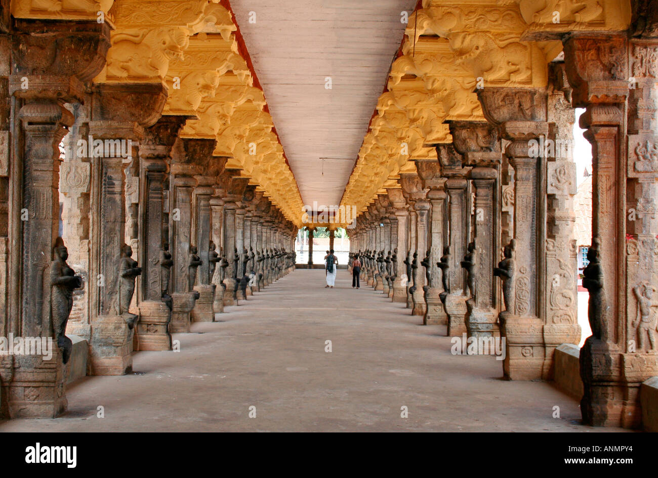People seen walking through a long passage lined on both sides by stone ...