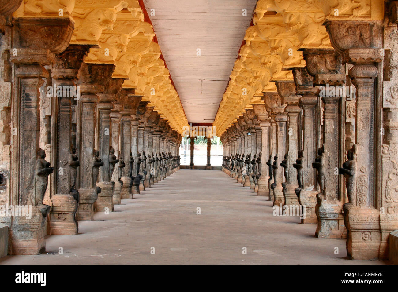 A long passage lined on both sides by stone pillars with sculptures in ...