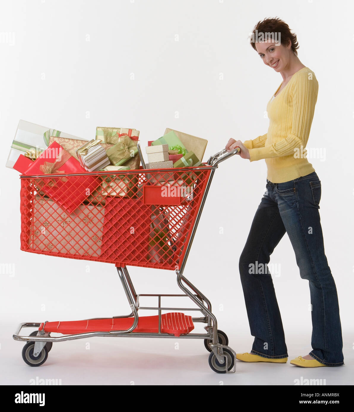Woman pushing shopping cart of gifts Stock Photo - Alamy