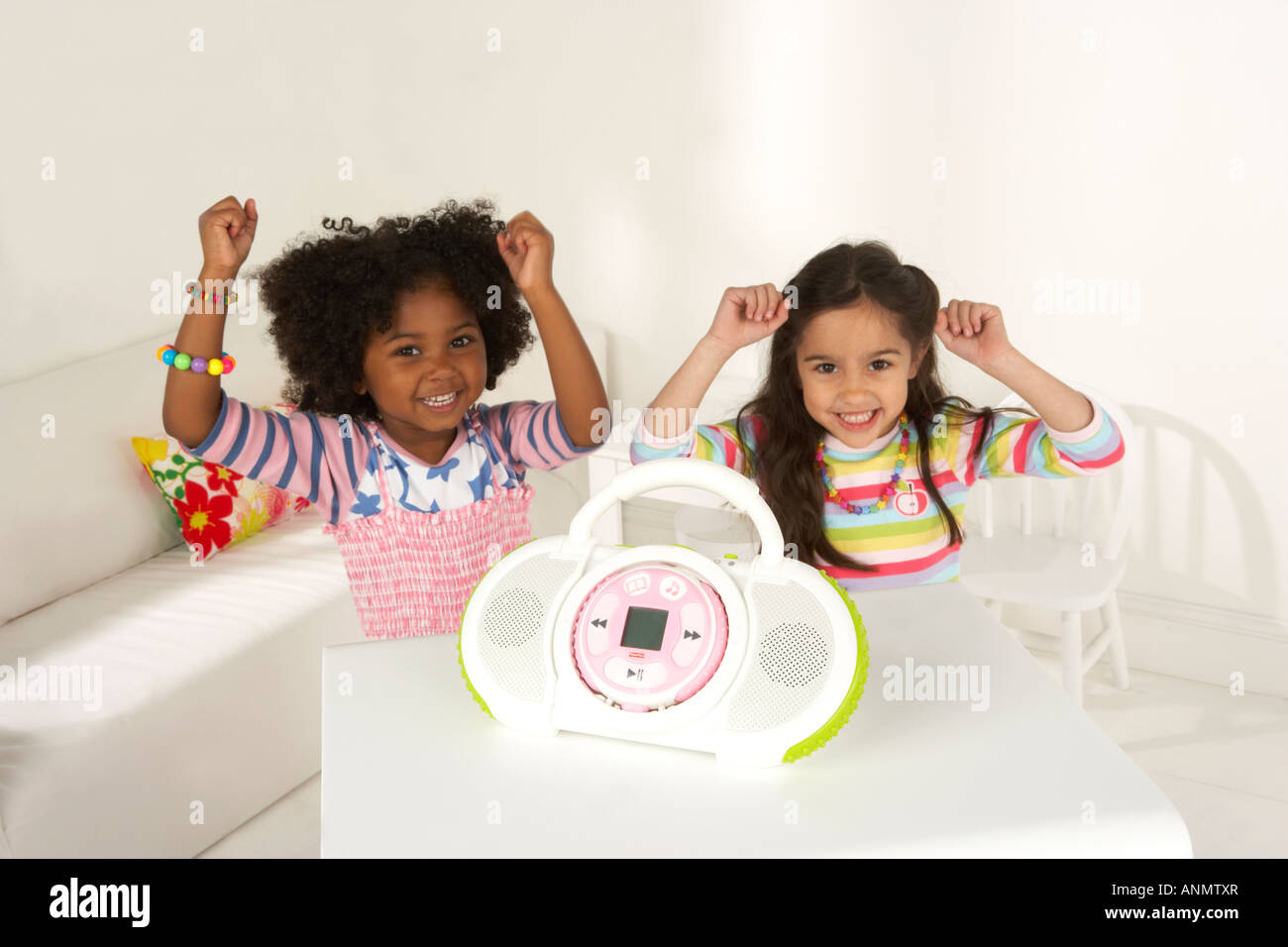 two girls dance and cheer as they listen to music on a CD player Stock ...
