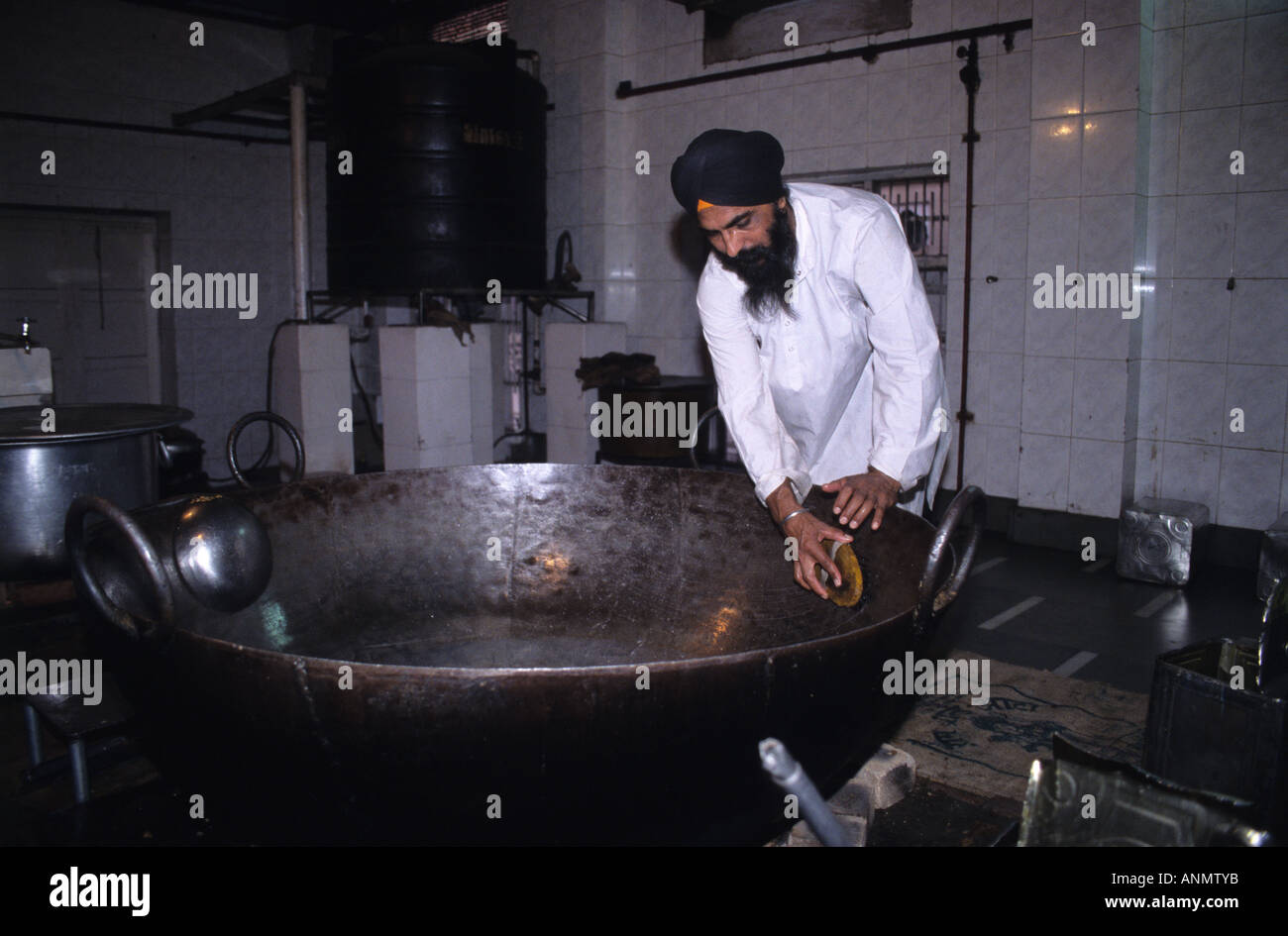 Sikh cleaning giant pot in temple kitchen Stock Photo - Alamy