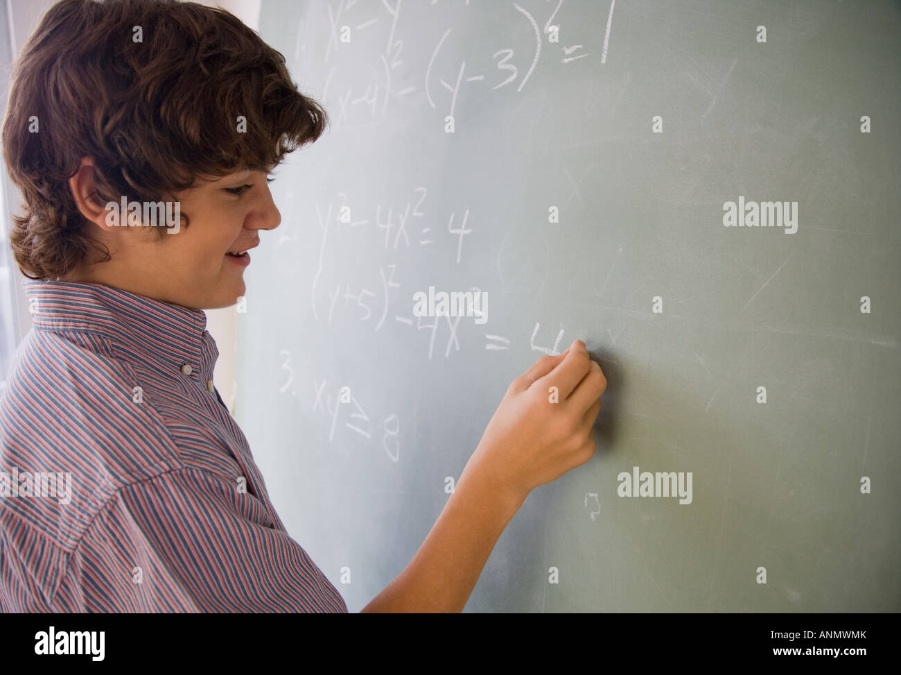 Teenaged boy writing math equations on blackboard Stock Photo - Alamy