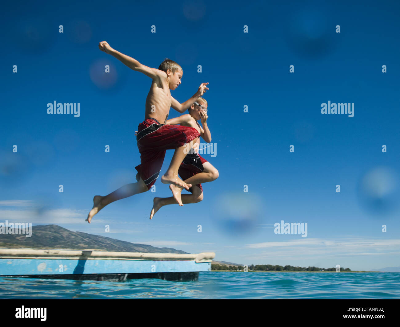 Brothers jumping off dock into lake, Utah, United States Stock Photo ...