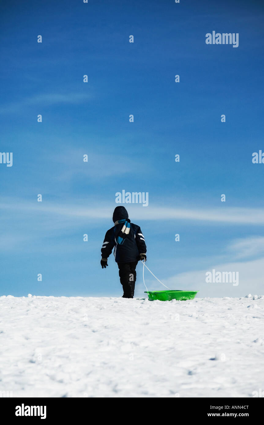 Child pulling sled on snow Stock Photo - Alamy