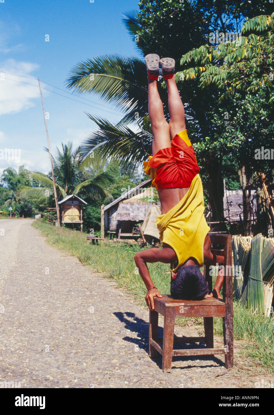 young boy doing head stand on chair, Laos Stock Photo - Alamy