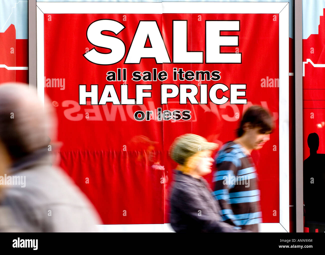 Shoppers walk passed a sale sign in a store window in Birmingham UK ...