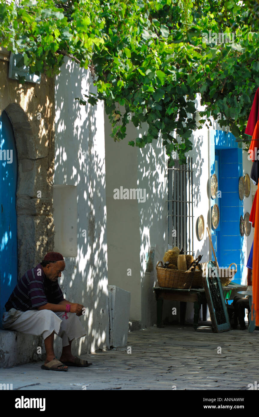 A man sits on his doorstep in the medina of Mahdia Stock Photo - Alamy