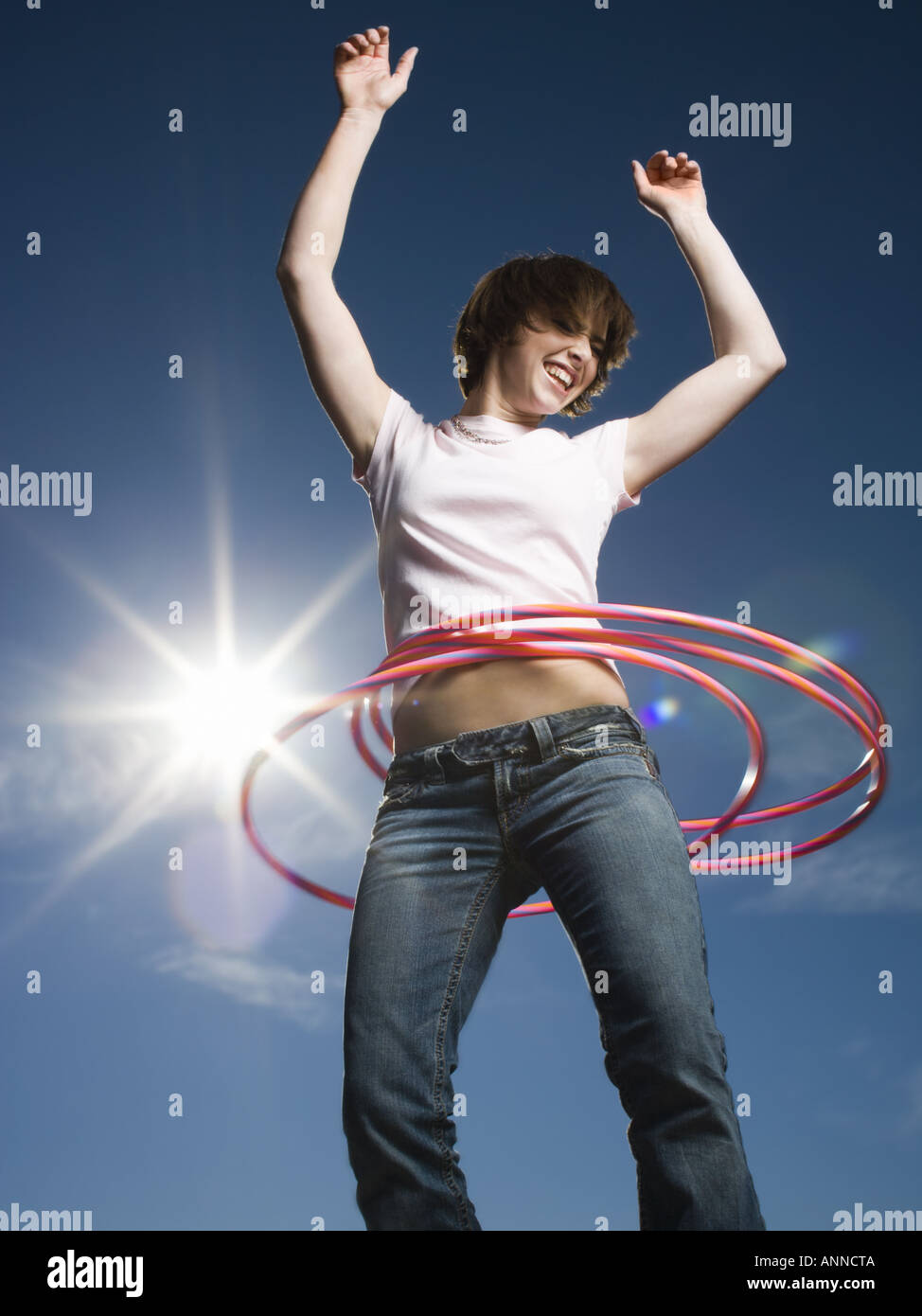 Low angle view of a teenage girl spinning hula hoops around her waist ...