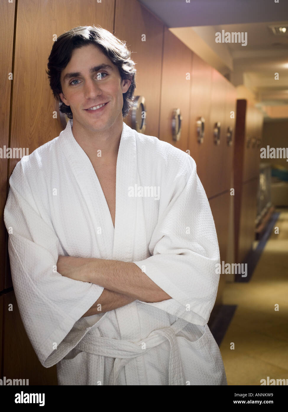 Portrait of a young man leaning against a wooden wall with his arms ...