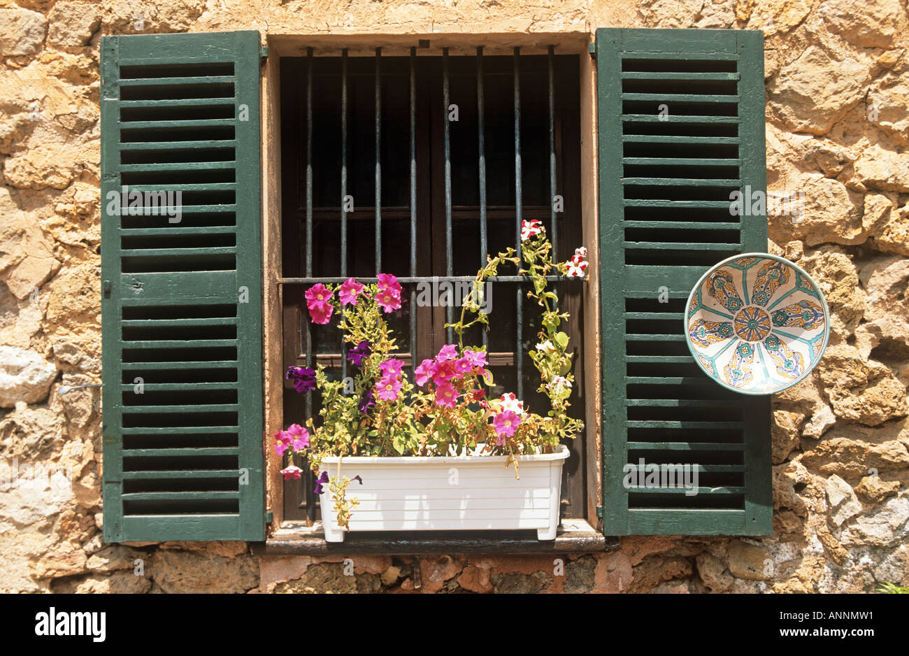 A window with a decorative ceramic bowl fixed to the green shutters ...