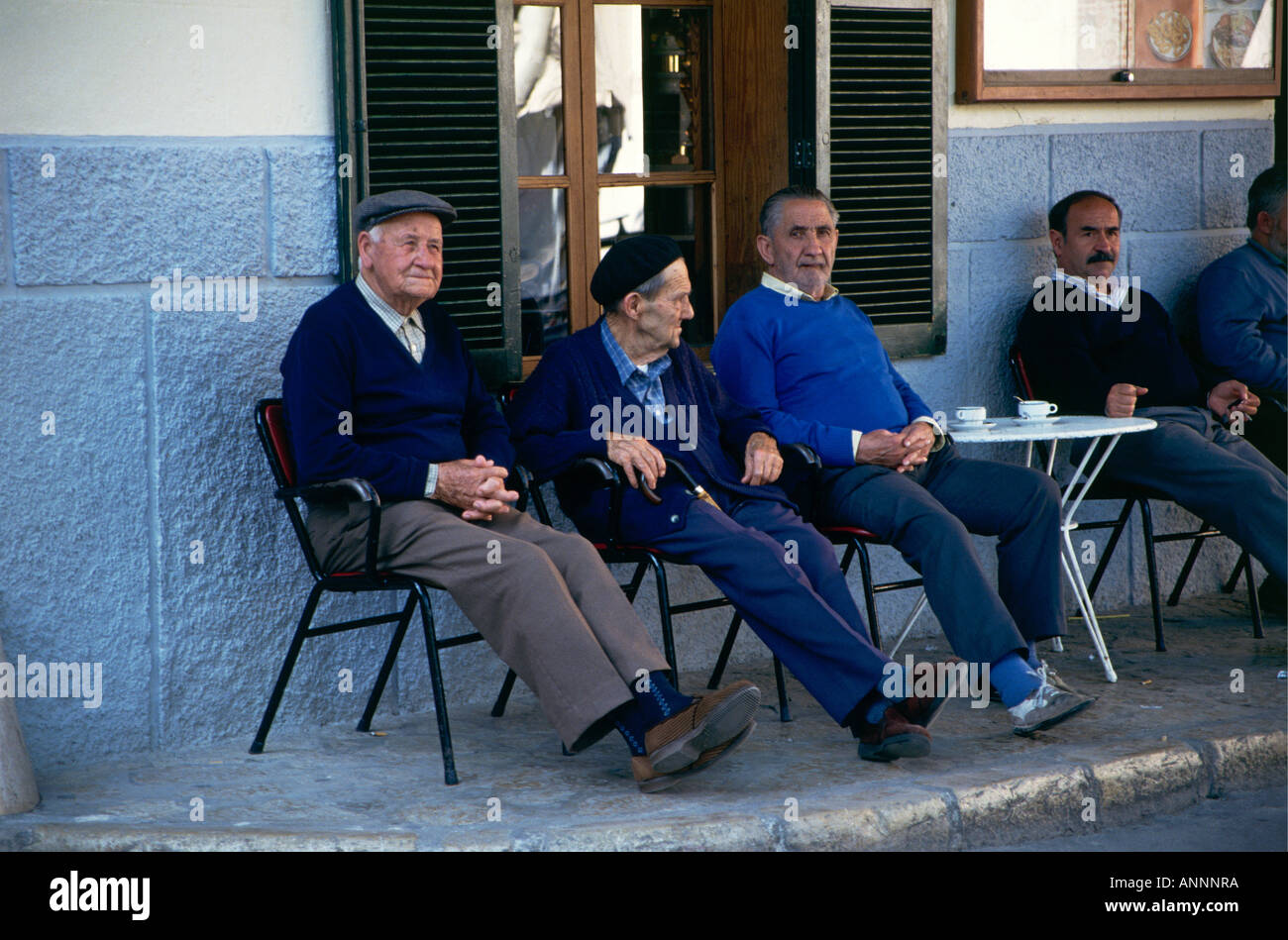 Three men chatting and watching the world go by from a table on the ...