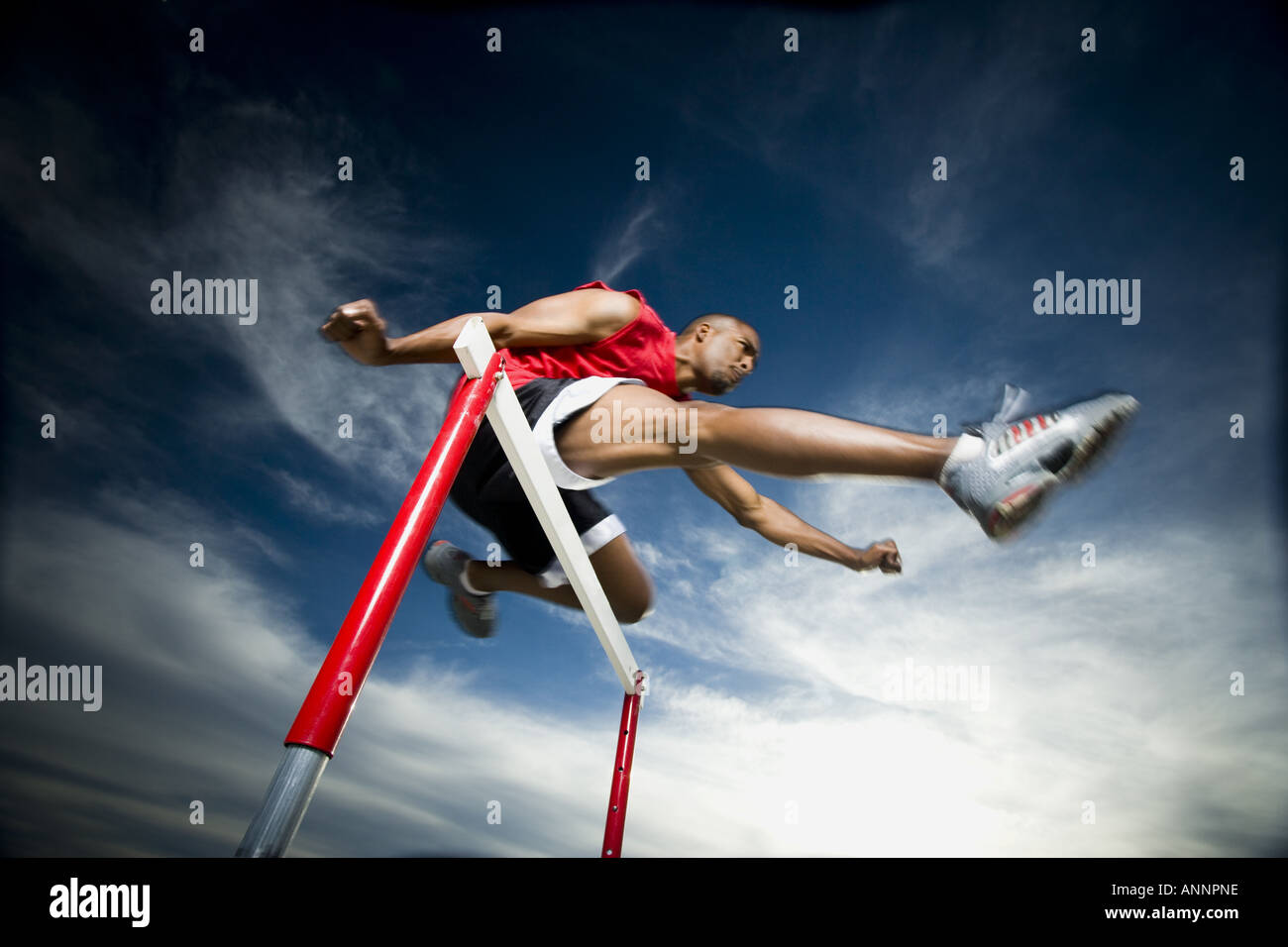 Low angle view of a young man jumping over a hurdle in a race Stock ...