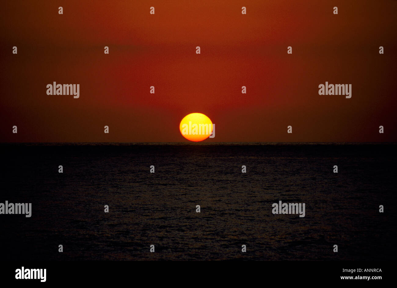 Golden orange sun setting into the sea evening sunset sky Isla Espanola ...