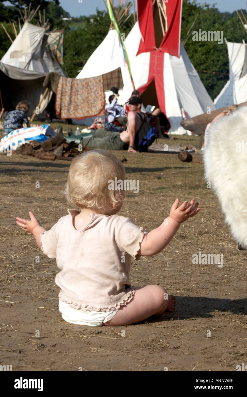 Teepee or tipi village field with people and young baby in act of ...