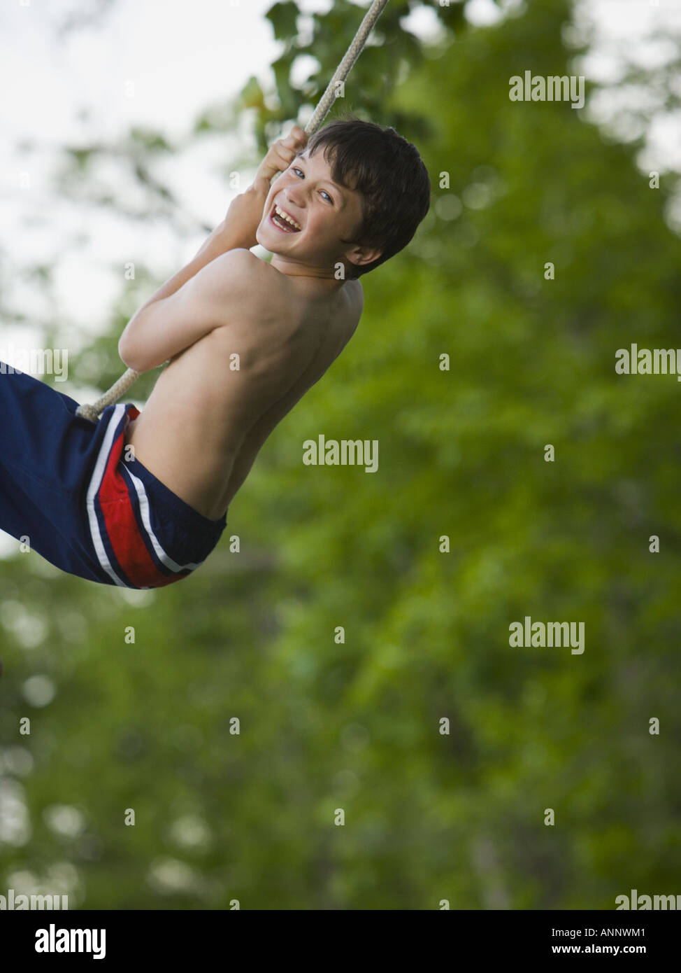 Portrait of a boy swinging on a rope Stock Photo - Alamy