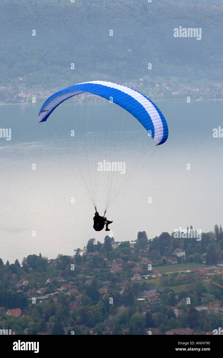 Paragliding pilot flying blue paraglider towards Lac de Annecy in ...