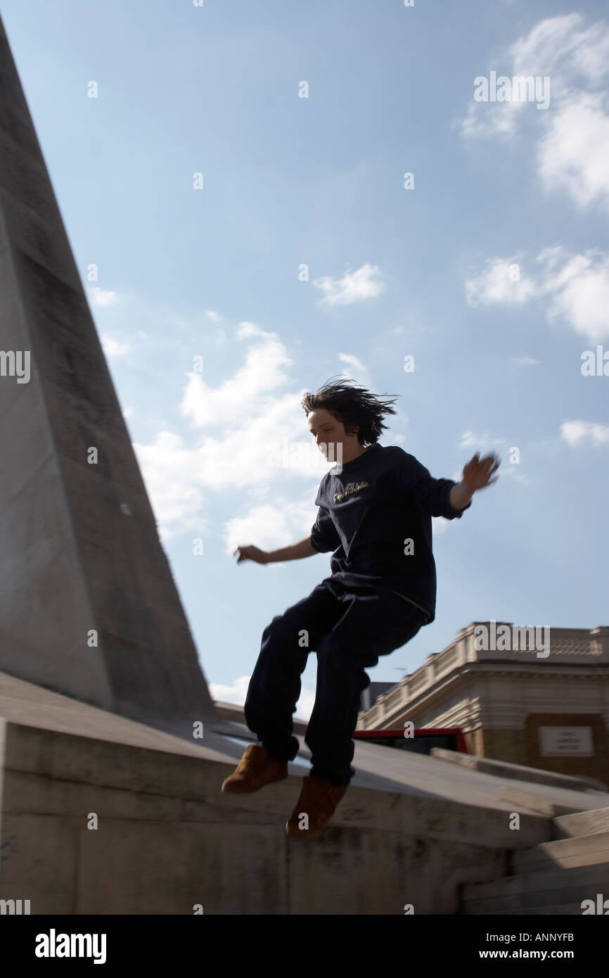 Boy or young man doing stunt skateboard jump from steps near London ...
