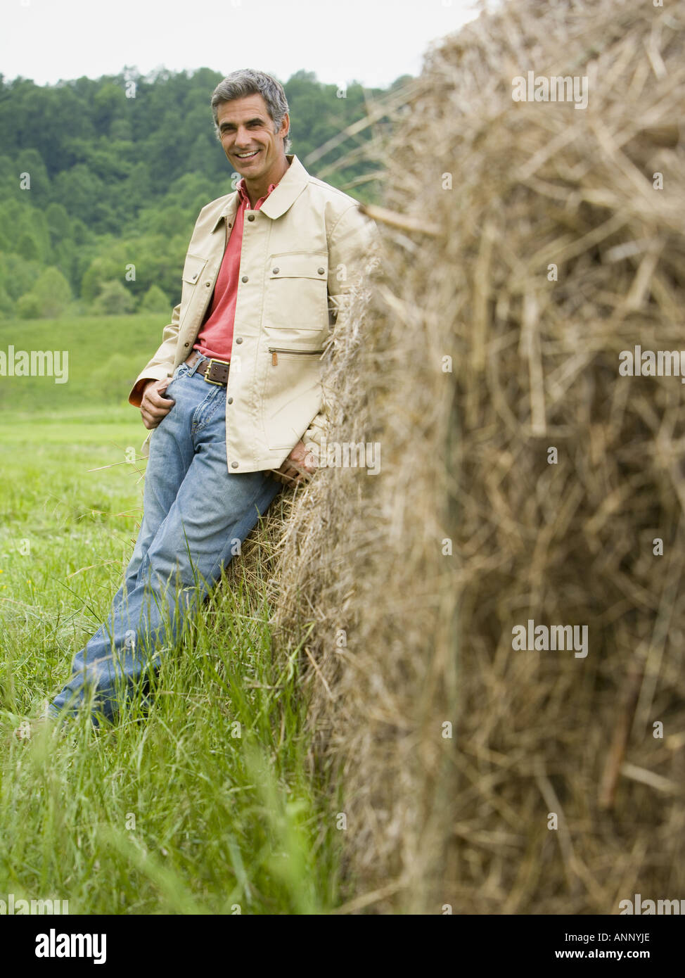 Portrait of a man leaning against a hay bale Stock Photo - Alamy