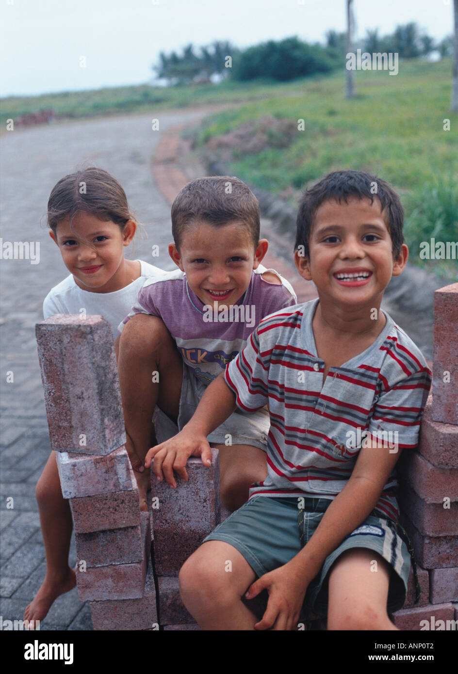 Portrait of two boys and a girl sitting on bricks Stock Photo - Alamy