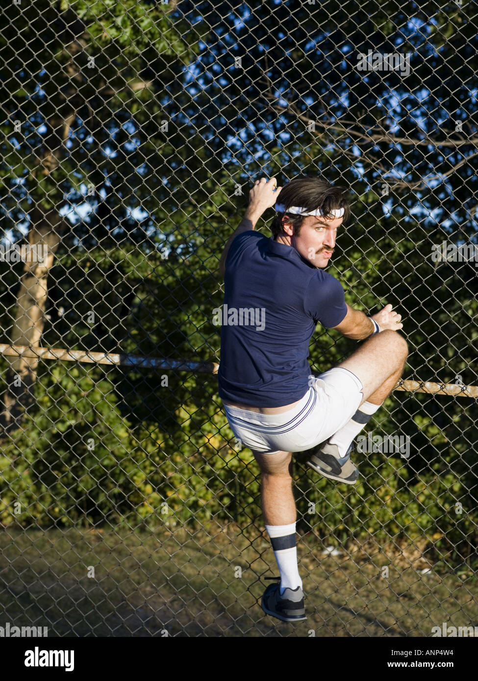 Young man climbing a chain link fence Stock Photo - Alamy