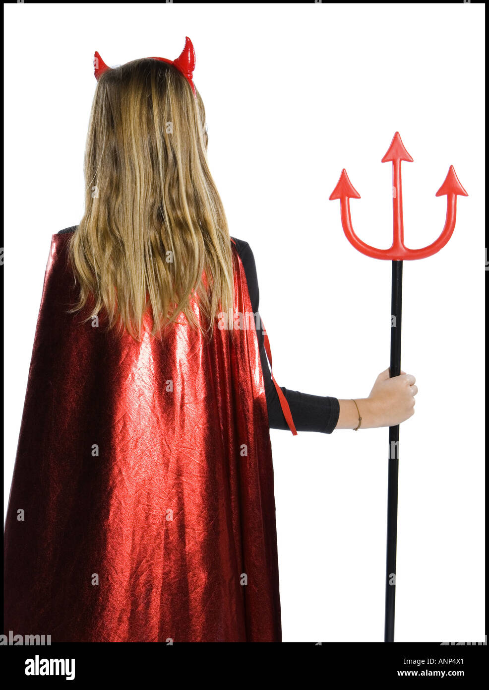 Rear view of a teenage girl wearing a devil costume holding a pitchfork ...