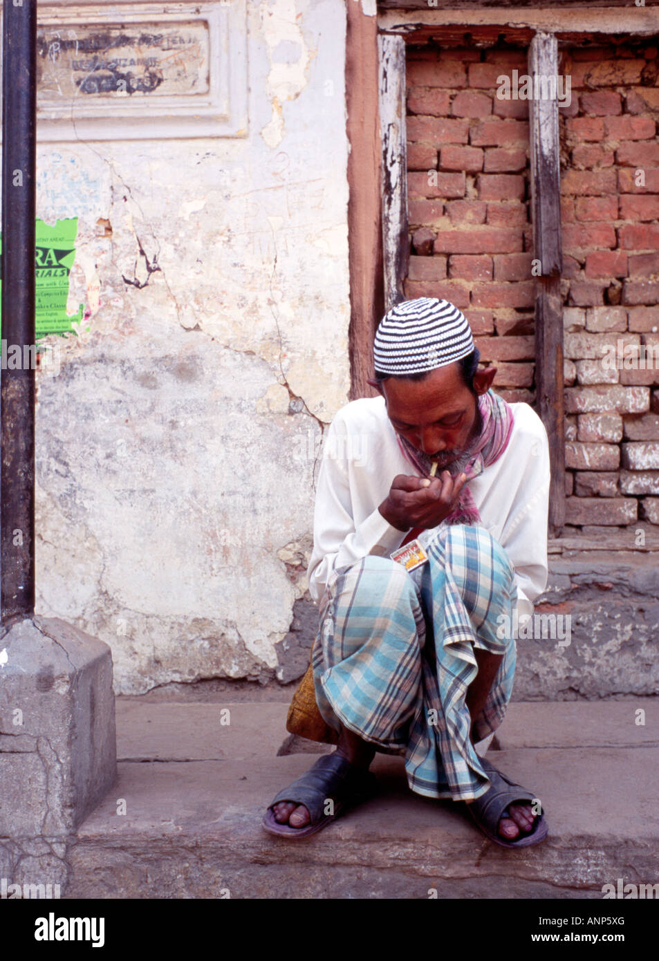 Indian man crouching on wall smoking, India Stock Photo - Alamy