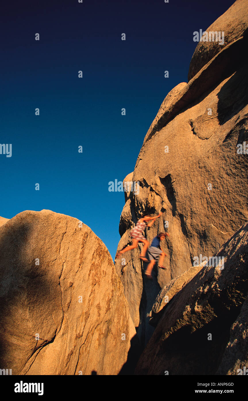 Low angle view of two people jumping over a gap between rocks Stock ...