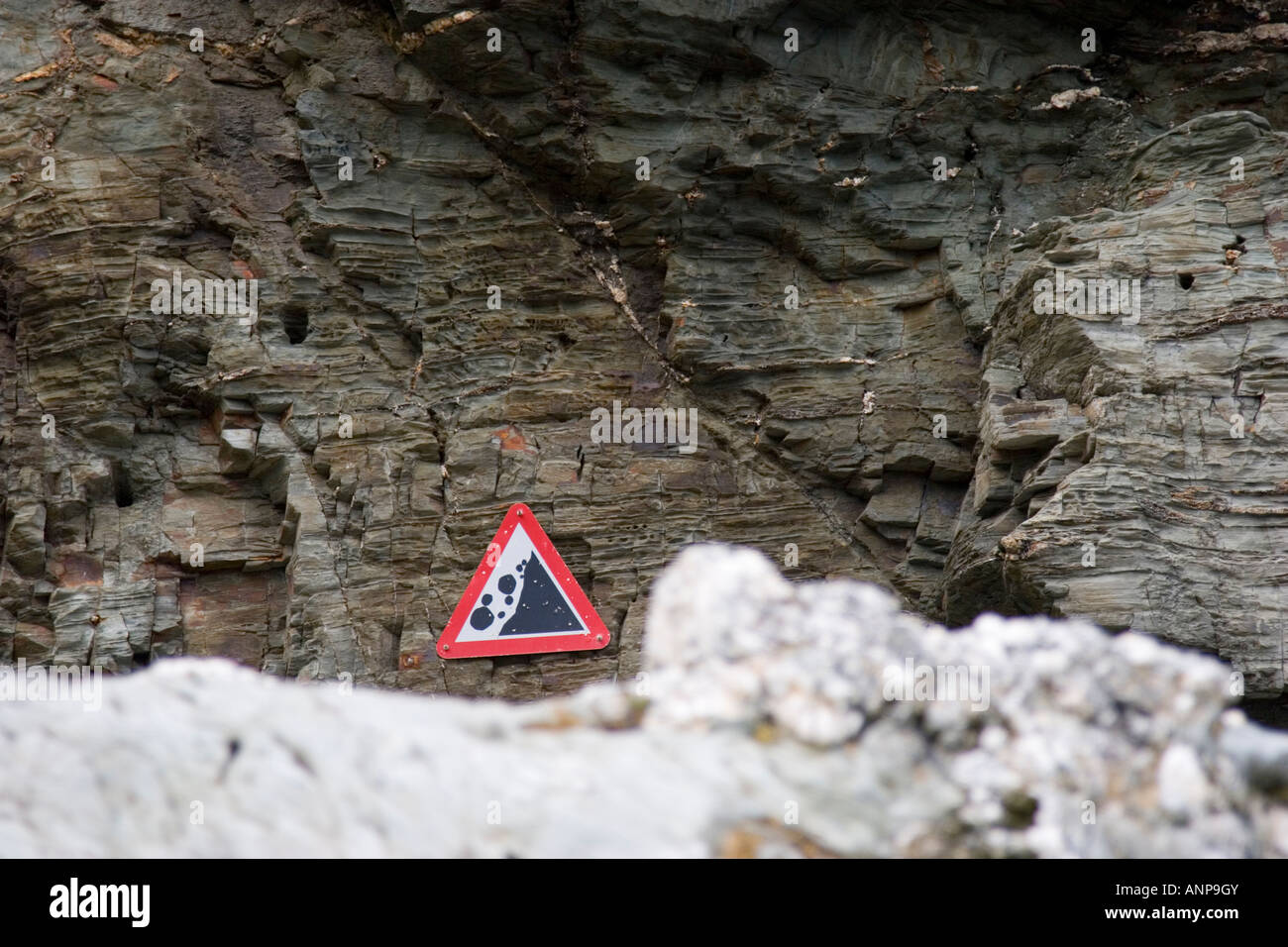 Sign attached to sheer cliff face warning of falling rocks Stock Photo ...