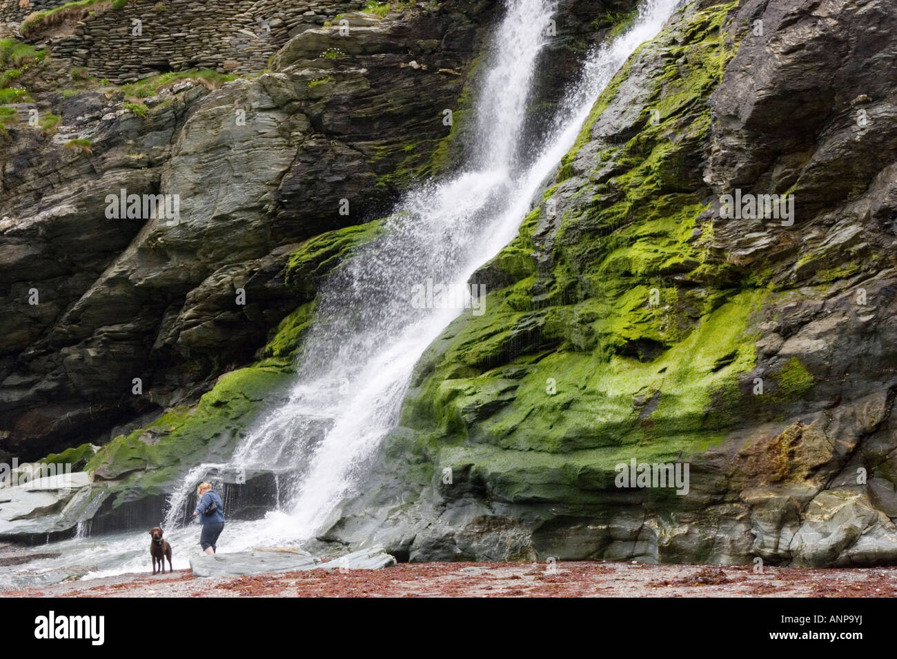 Waterfall cascading onto the beach underneath the ancient castle in ...