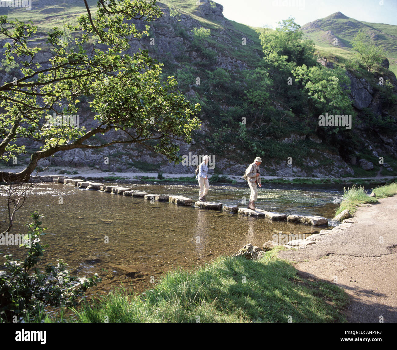 Walkers crossing River Dove stepping stones in Dovedale Peak District ...