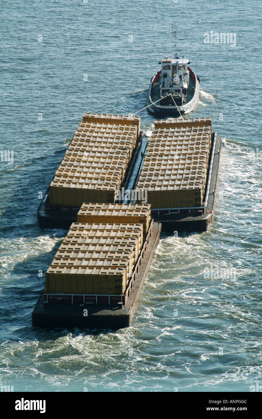 Looking down at tug boat pulling barges loaded with containers full of ...