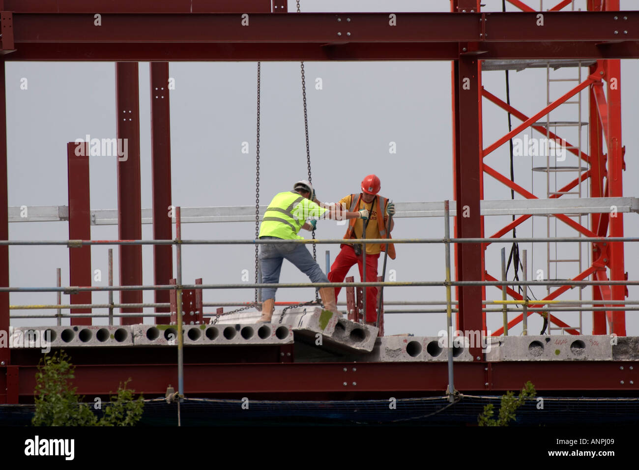 Construction workers moving a concrete floor beam into place on a ...