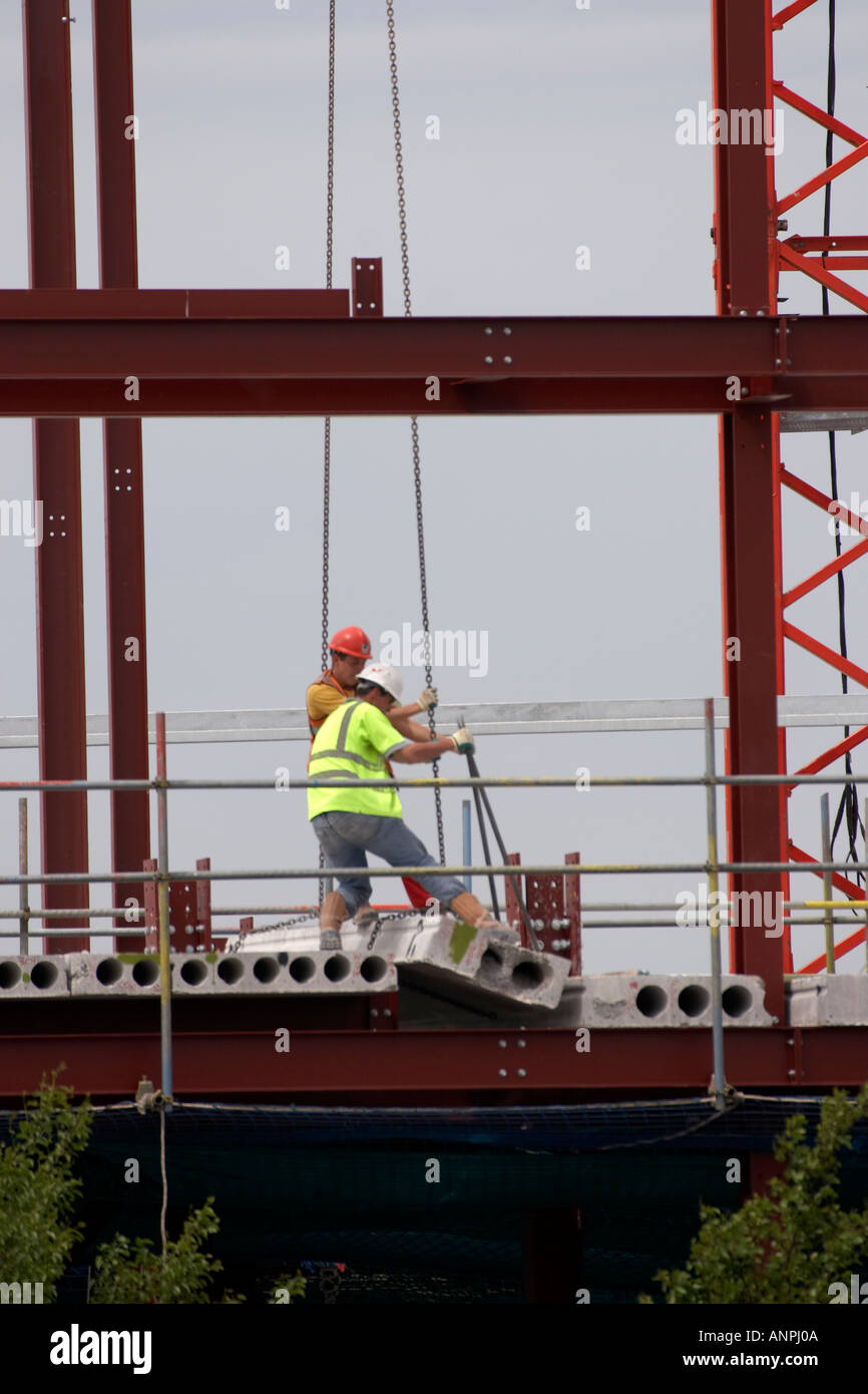Construction workers moving a concrete floor beam into place on a ...