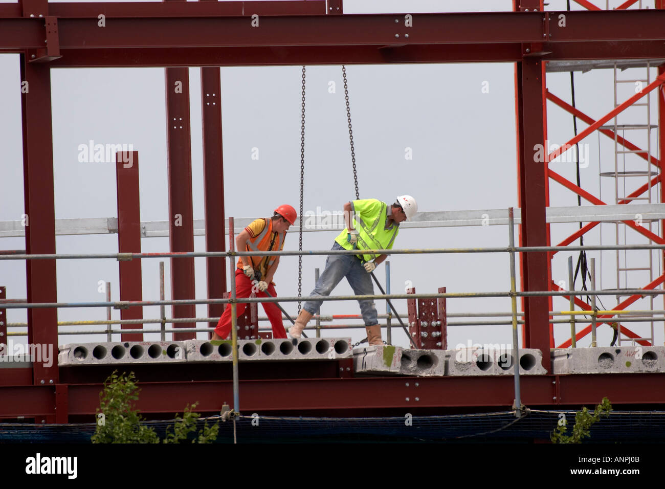 Construction workers moving a concrete floor beam into place on a ...