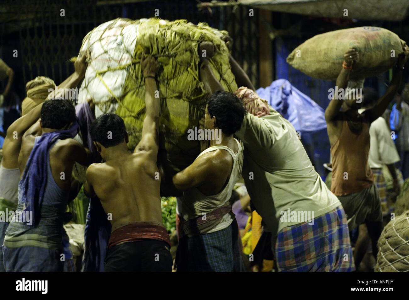 Men lift a heavy weight at the wholesale market for fruit and ...