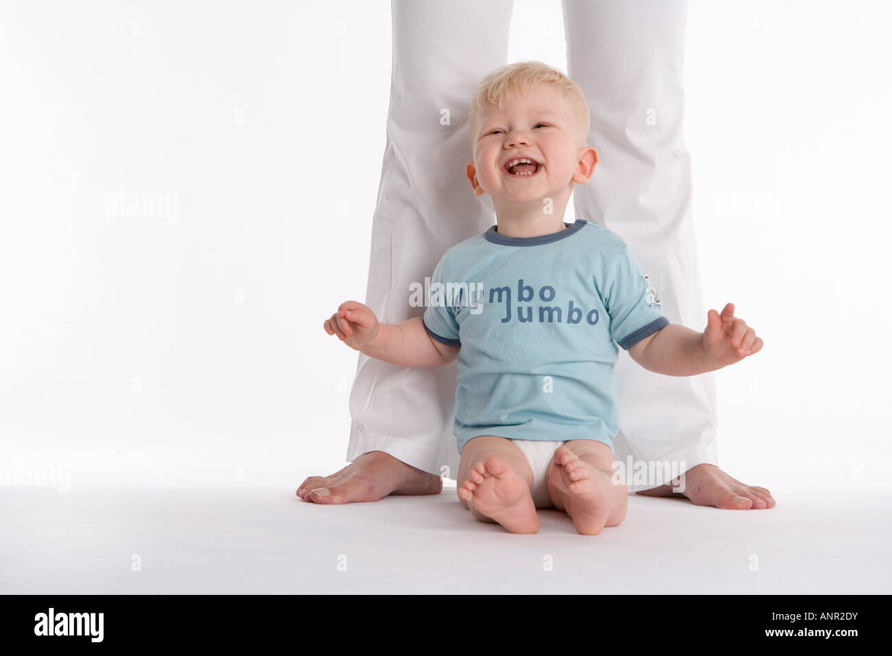 Little boy sitting in front of his parents legs Stock Photo - Alamy