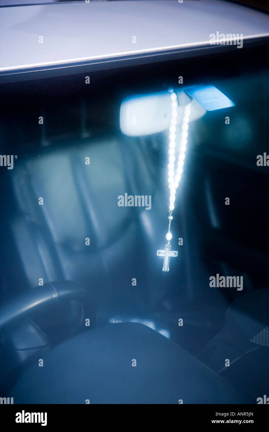 Crucifix hanging from a car rear view mirror Stock Photo - Alamy