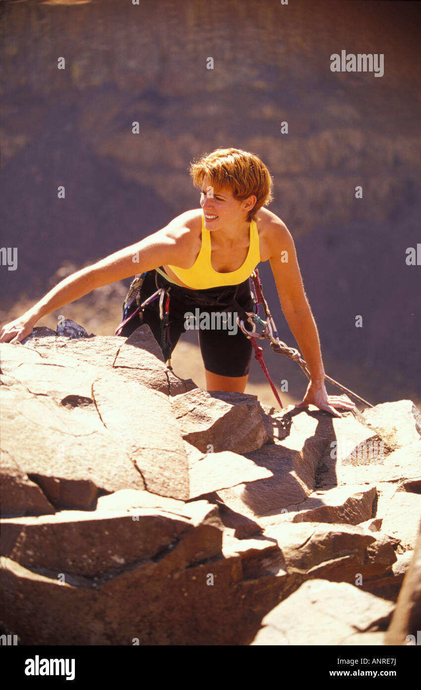 A woman rock climber successfully summits a basalt column in central ...